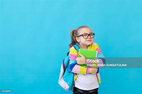 줄무늬 재킷과 배낭에 안경을 가진 귀여운 어린 소녀의 초상화 교육의 개념 사진 스튜디오 파란색 배경 텍스트 장소 6 7 살에 대한 스톡 사진 및 기타 이미지 Istock