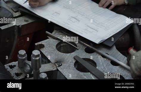 Two Workers Are Discussing A Technical Drawing A Controller Is Making