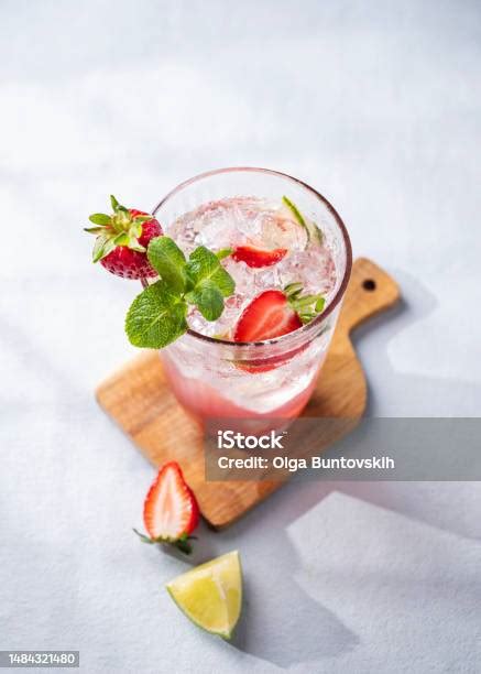 신선한 딸기 모히토는 그림자가 있는 밝은 배경에 베리 라임 민트 얼음이 있는 유리에 담겨 있습니다 파티를 위한 여름 상쾌한 음료의 개념 평면도 딸기에 대한 스톡 사진 및