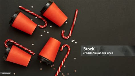 검은 색 배경에 사탕수수와 종이 커피 컵 크리스마스 사탕 지팡이와 스타 색종이와 크리스마스 배경 상단보기 플랫 레이 모형 텍스트의 공간을 복사합니다 커피 마실 것에 대한