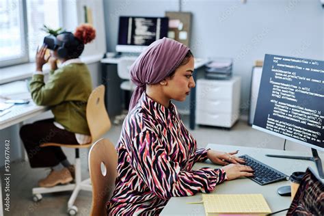 Side View Portrait Of Muslim Young Woman As Software Developer Writing Code And Using Computer