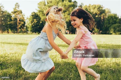 공원의 녹색 잔디에서 춤을 추고 함께 노는 두 어린 소녀의 이미지 공원에서 여름날을 즐기는 아이들 두 자매는 자연 배경에 재미를 어린 시절과 우정 2명에 대한 스톡 사진 및