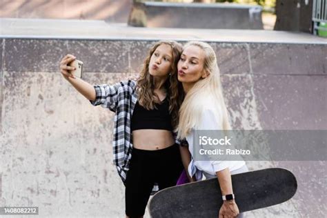 스케이트와 페니 보드가있는 어머니와 어린 딸이 스케이트 파크에서 전화로 셀카를 만들고 있습니다 극단적 인 라이프 스타일 엄마와 아이의 가족은 함께 시간을 보낸다 10 11