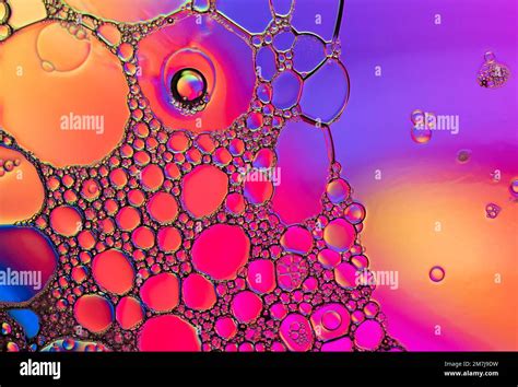 Colourful Light Diffraction Patterns Formed By Oil Droplets Floating On Water Above A Coloured
