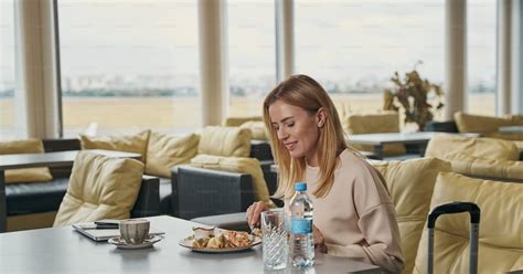 웃고 있는 젊은 여자는 공항 카페에서 크레페를 먹는 테이블에 앉아 있다 사진 Unsplash의 카페테리아 이미지