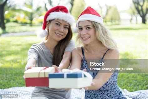 산타 모자를 착용 하 고 선물 상자를 주는 행복 한 예쁜 여자 2명에 대한 스톡 사진 및 기타 이미지 2명 개념 공원 Istock