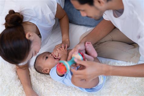엄마와 아버지는 웃는 즐거운 자랑스러운 놀림 키스 뺨과 발 팔을 잡고 침대에서 새로 태어난 아시아 유아 아기를 잡고 가족에 대한 스톡 사진 및 기타 이미지 Istock