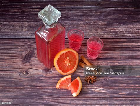 나무 테이블 위에 두 개의 크리스탈 잔과 수제 리큐어가 담긴 디캔터가 놓여 있고 그 옆에는 잘 익은 자몽 계피 스틱 아니스 조각이 놓여 있습니다 0명에 대한 스톡 사진 및