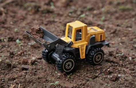 Yellow Wheel Loader Or Tractor Toy On Soil Or Ground Background