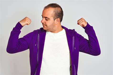 보라색 스웨트셔츠를 입은 청년이 고립된 흰색 배경 위에 서서 자랑스럽게 웃고 있는 팔 근육을 보여줍니다 피트니스 개념입니다 개념에 대한 스톡 사진 및 기타 이미지 Istock