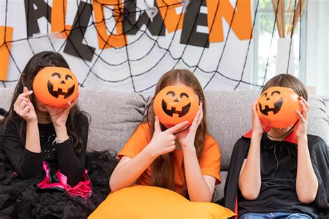 할로윈 파티 동안 거실에서 소파에 의상을 입은 행복한 귀여운 어린이 소년과 소녀 호박 잭 오 랜턴 커버 얼굴 10월에 대한 스톡 사진 및 기타 이미지 Istock