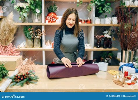 El Vendedor De Sexo Femenino Envuelve La Caja De Regalo En Papel Festivo Foto De Archivo