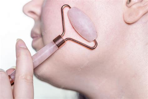 Premium Photo Woman Massages Cheek With Quartz Roller Massager