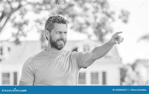 Happy Bearded Man Looking Forward And Pointing Finger Directing Stock
