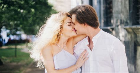 햇볕이 잘 드는 녹색 거리에서 걷고 부드럽게 포옹하는 사랑에 빠진 아름다운 행복한 커플 세련된 힙스터 신랑과 금발 신부가 포옹 휴가 중 여름 도시 거리의 낭만적 인 순간