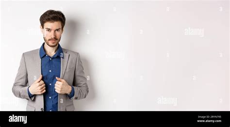 Confident Young Man With Beard Fixing Suit And Looking Sassy At Camera Feeling Ready And