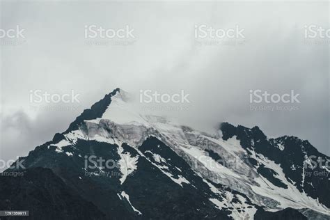 낮은 구름에 큰 눈 덮인 산 꼭대기와 미니멀 한 흑백 대기 산 풍경 바위에 빙하와 멋진 최소한의 풍경 구름에 눈이 있는 푸른 흰색 높은 산 의 정점 0명에 대한 스톡 사진