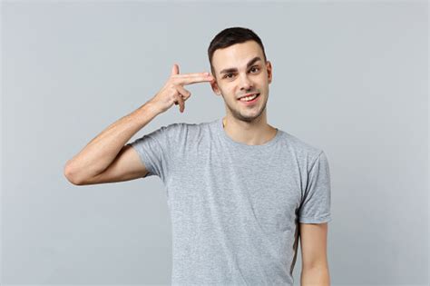 캐주얼 복장에 웃는 젊은 남자의 초상화는 그가 스튜디오에서 회색 배경에 고립 촬영에 대 한 것 처럼 머리에 손가락을 포인트 사람들은 진심으로 감정 라이프 스타일 개념입니다