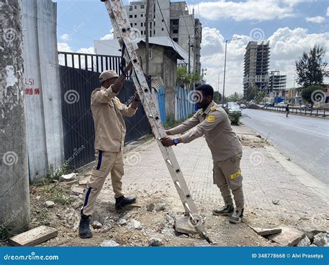 Two Security Guards Are Holding A Ladder To Prevent Accidents To People