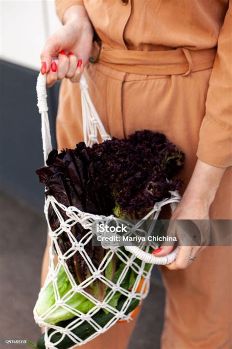 소녀는 비닐 봉지없이 야채 채소와 메쉬 쇼핑 백을 들고있다 제로 폐기물 플라스틱 무료 환경 친화적 인 개념 수제 마크라메 백 지속 가능한 라이프 스타일 가방에 대한 스톡