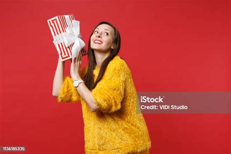 빨간 벽 배경에 고립 된 선물 리본 빨간 줄무늬 선물 상자를 들고 잠겨있는 호기심 젊은 여자 발렌타인 데이 국제 여성의 날 생일 휴일 개념입니다 복사 공간을 모의 합니다