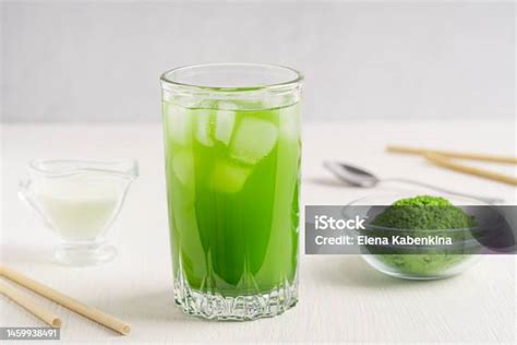 녹차 잎 가루와 우유를 섞어 만든 유기농 말차 라떼 한 잔이 흰색 나무 테이블에 제공됩니다 가루로 빻은에 대한 스톡 사진 및