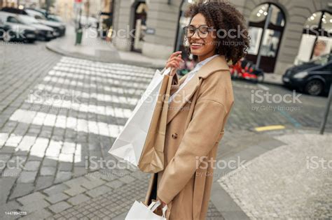 패션 아프리카 미국 여자는 종이 봉지로 성공적인 쇼핑 후 도시에서 길을 건너 25 29세에 대한 스톡 사진 및 기타 이미지 25 29세 Theatrical
