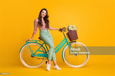 생생한 노란색 배경에 고립 된 미소 꽃바구니와 자전거에 앉아 예쁜 여자의 전체 길이 몸 크기 사진 두발자전거에 대한 스톡 사진