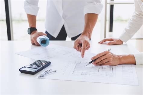 Premium Photo Cropped Image Of Engineers Discussing Over Blueprint In Office