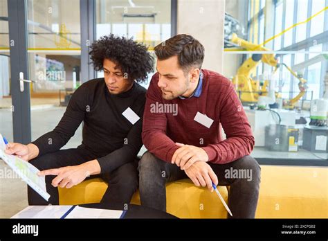 two engineers analyzing documents and discussing the programming and