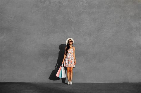 젊은 여성 여름 모자와 안경을 입고 많은 다른 쇼핑 백을 들고 회색 벽에 쇼핑을 즐기는 행복한 젊은 여성 가방에 대한 스톡 사진 및 기타 이미지 Istock