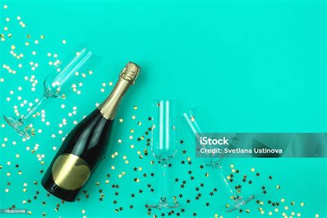 황금 별 모양의 색종이와 트렌디 한 민트 배경에 샴페인 병과 세 잔 휴일 개념입니다 디자인에 대한 모형 플랫 레이 스타일입니다