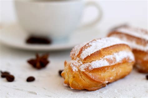 흰색 배경에 접시에 가까운 바닐라 에클레어 커피 콩과 아니스 스타 흰색 테이블에 계피 스틱 커피 컵 복사 공간을 복사합니다 전통적인 프랑스 맛있는 디저트 0명에 대한 스톡