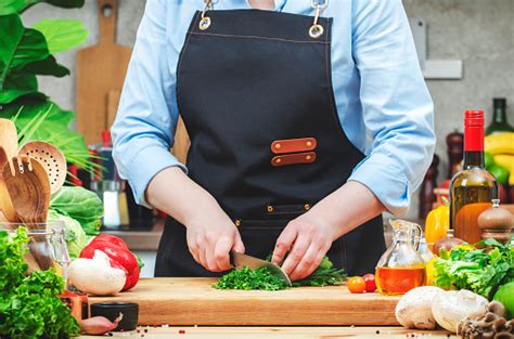 파슬리를 요리하십시오 그리고 셰프 나이프로 딜 나무 테이블 주방용품 야채 허브 요리 재료가 있는 아늑한 주방 건강한 채식주의자 식사 요리 요리법 음식 블로깅 가정 주방에