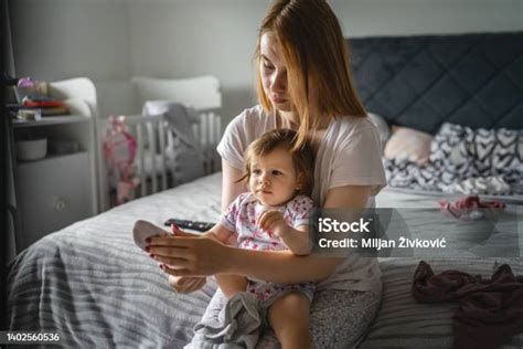 그녀의 어머니가 옷을 갈아 입고있는 동안 집에서 침대에 앉아있는 한 작은 백인 소녀 유아는 복사 공간을 자라는 실제 사람들 12