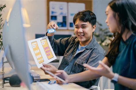 Asian Ui Ux Designers Discussing Mobile App Design In Modern Office Brainstorming Planning