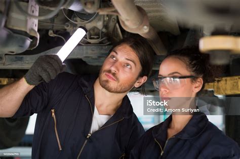 팀 기술자 노동자는 리프트 된 자동차 아래의 유지 보수 자동차 엔진을 확인합니다 자동 모터 차고에서 유지 보수 차량을위한 렌치