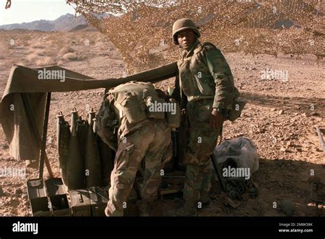 Two Gun Crewmen In Front Of A Stand Of 155 Mm Projectiles Including