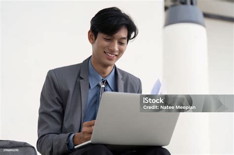 현대적인 야외 비즈니스 환경에서 노트북으로 작업하면서 미소 짓고 있는 젊은 아시아 사업가 Office For National Statistics에 대한 스톡 사진 및 기타