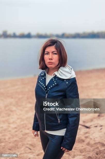 검은 재킷을 입은 어린 예쁜 소녀가 물 근처의 모래 해변에 서 있습니다 가까운에 대한 스톡 사진 및 기타 이미지 가까운 가을 가죽 Istock