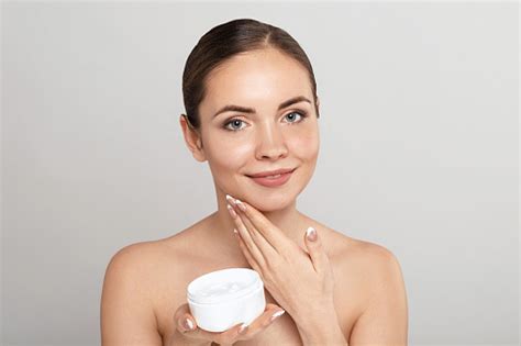 뷰티 페이스 오브 우먼 컨셉 스킨 케어 화장품 보습 크림을 들고 적용한 여성 모델의 초상화와 얼굴을 만져보실 수 있습니다 피부 보호 미용 술 스파 보습제에 대한 스톡 사진