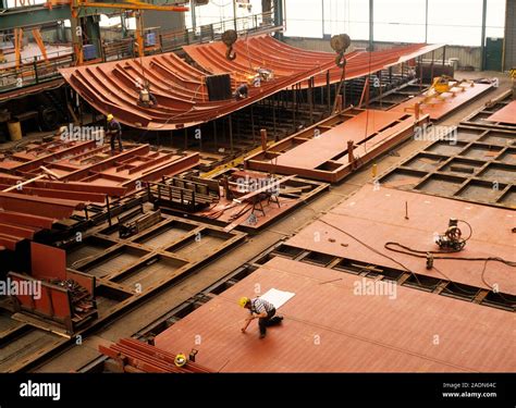 Shipbuilding Workers Welding The Prefabricated Segments Of A Ships Hull In A Dry Dock In