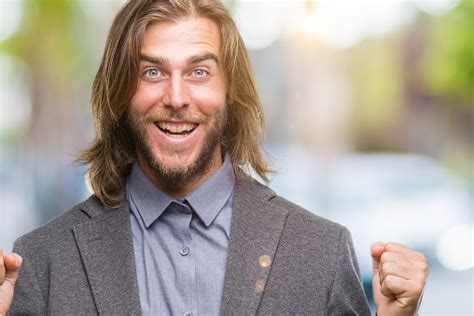 축 하 하는 고립 된 배경 위에 긴 머리를 가진 젊은 잘생긴 사업가 놀라게 무기 제기와 성공을 위한 깜짝 놀라게 고 눈을 엽니다 우승자 개념입니다 경영자에 대한 스톡 사진