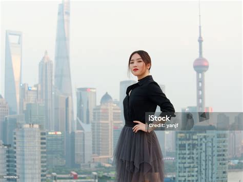 황혼 빛으로 배경이 흐릿한 상하이 번드 랜드 마크 건물 배경이있는 저택 지붕 꼭대기에서 검은 색의 아름다운 젊은 중국 여성 감정 사람 아름다움 및 라이프 스타일 개념