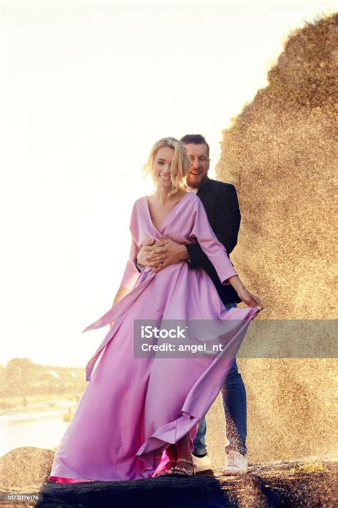 아름 다운 젊은 부부 포옹 하 고 멀리 고 서로 강에 낭만적인 데이트를 즐기고 남자와 여자에서 일몰 바다 근처의 태양에서 바위에 서 2명에 대한 스톡 사진 및 기타 이미지