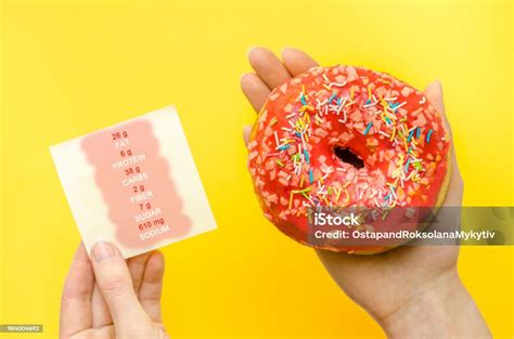 여성의 손을 잡고 뿌리와 핑크 유약된 도넛 영양 사실 여분의 칼로리 지방 노란 바탕에 건강에 해로운 패스트 푸드 초과 중량 개념에 대한 스톡 사진 및 기타 이미지 Istock