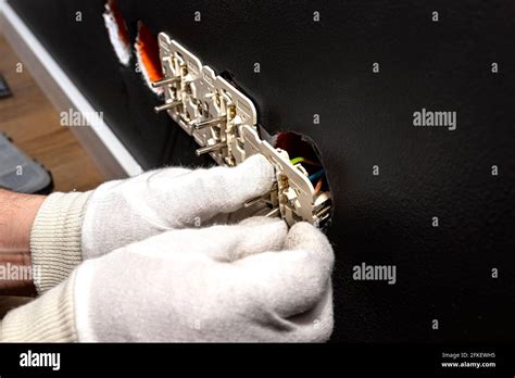 An Electrician Inserts A Double Grounded Electrical Socket Into An Electrical Box In The Black