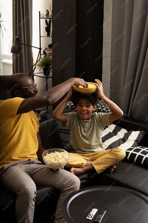 Pai E Filho Comendo Pipoca E Batata Frita Juntos No Sofá Foto Grátis