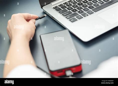 Woman Charges Her Laptop With Power Bank Using USB C Cable Stock Photo