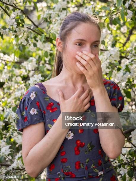 หญิงสาวจามในสวนสาธารณะกับพื้นหลังของต้นไม้ดอก ภูมิแพ้แนวคิดละอองเกสรดอกไม้ ภาพสต็อก ดาวน์โหลด